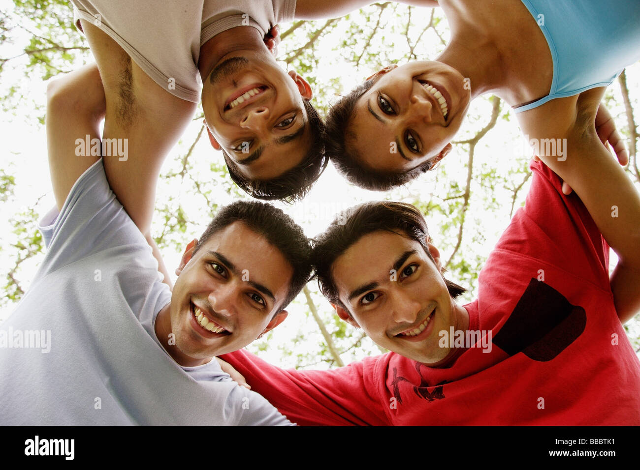 Circle of friends, arms around each other, looking down at camera Stock ...