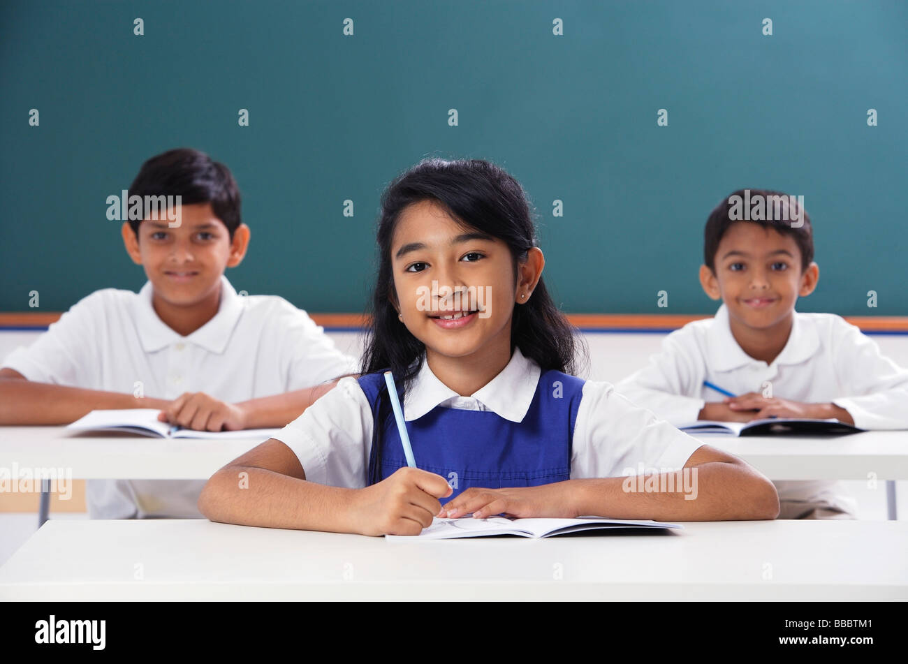 three students smile at camera, girl in center Stock Photo - Alamy