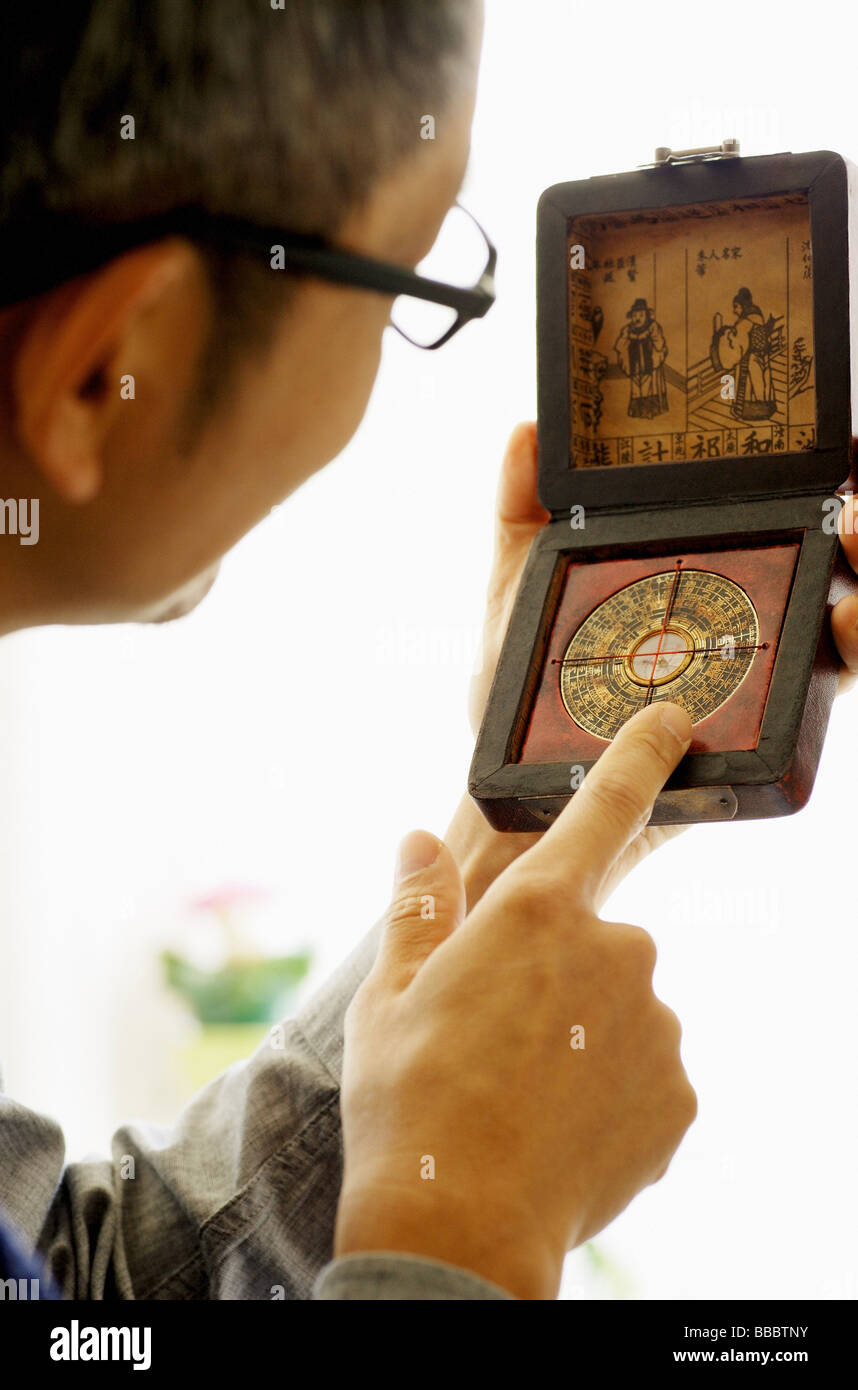 Man looking at Chinese compass Stock Photo - Alamy