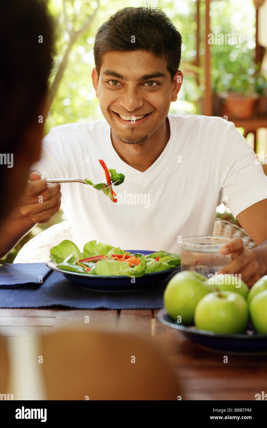 Man eating salad, looking at person opposite him Stock Photo - Alamy