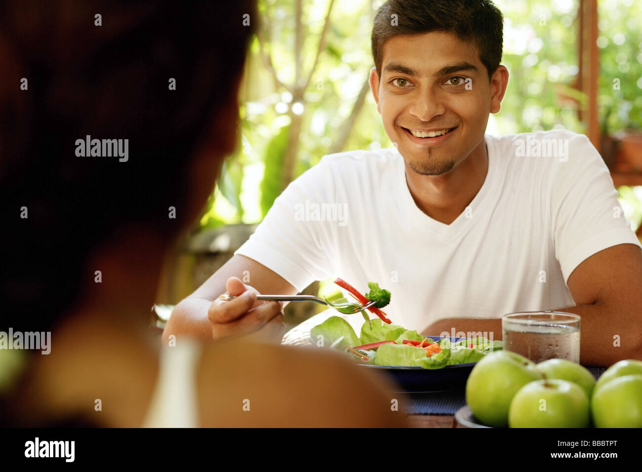 Man looking at person opposite him, salad in front of him Stock Photo ...