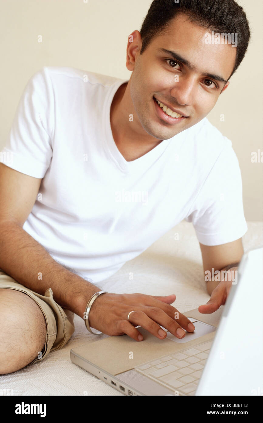 Man looking at camera, using laptop Stock Photo - Alamy