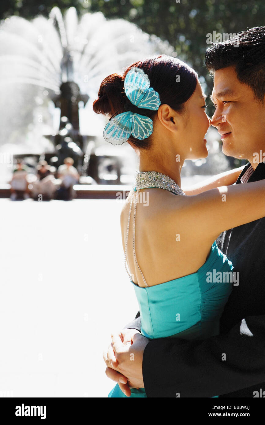 Couple hugging face to face, water fountain behind them Stock Photo - Alamy