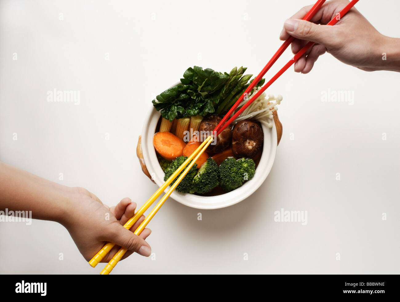 hands holding chopsticks in clay pot of vegetables Stock Photo - Alamy