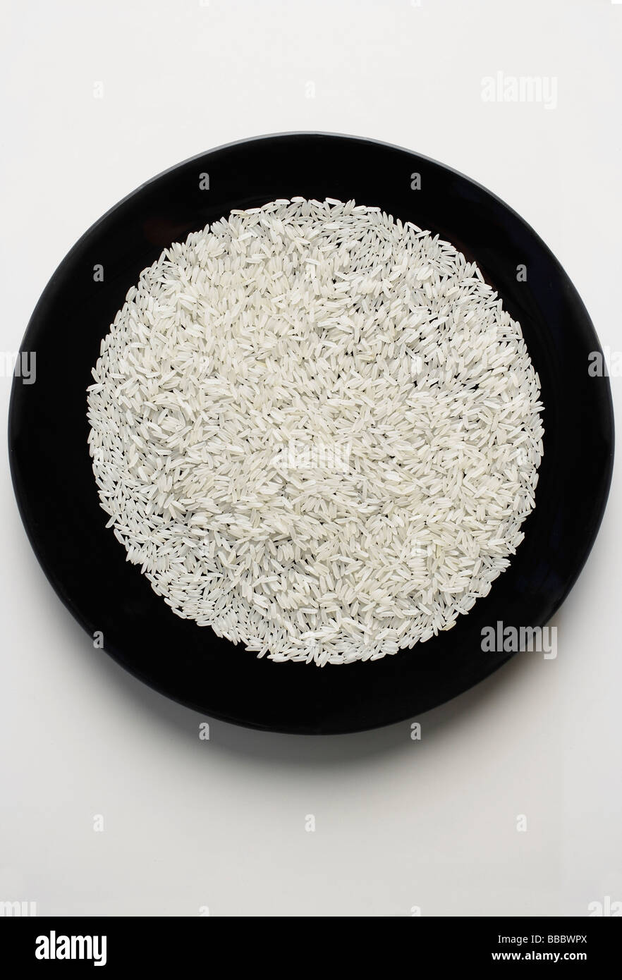 uncooked grains of rice spread out on a black plate Stock Photo - Alamy