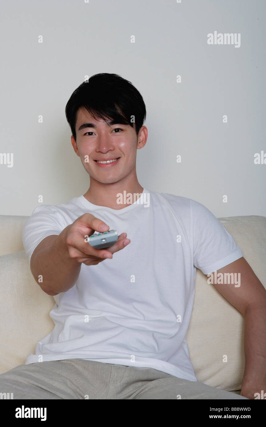 Young man, pointing TV remote control towards camera Stock Photo - Alamy