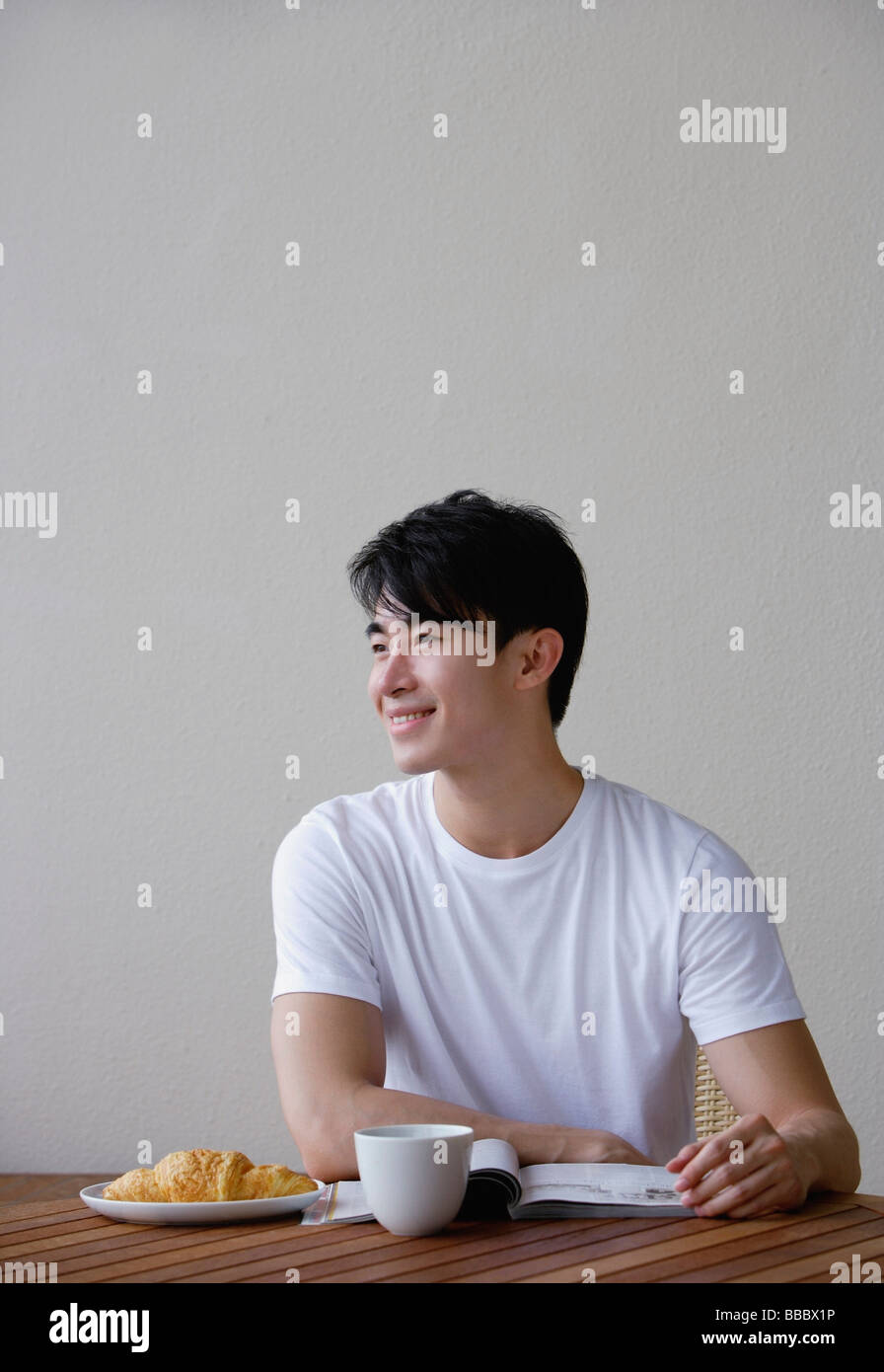 Young man having breakfast and reading a magazine Stock Photo - Alamy