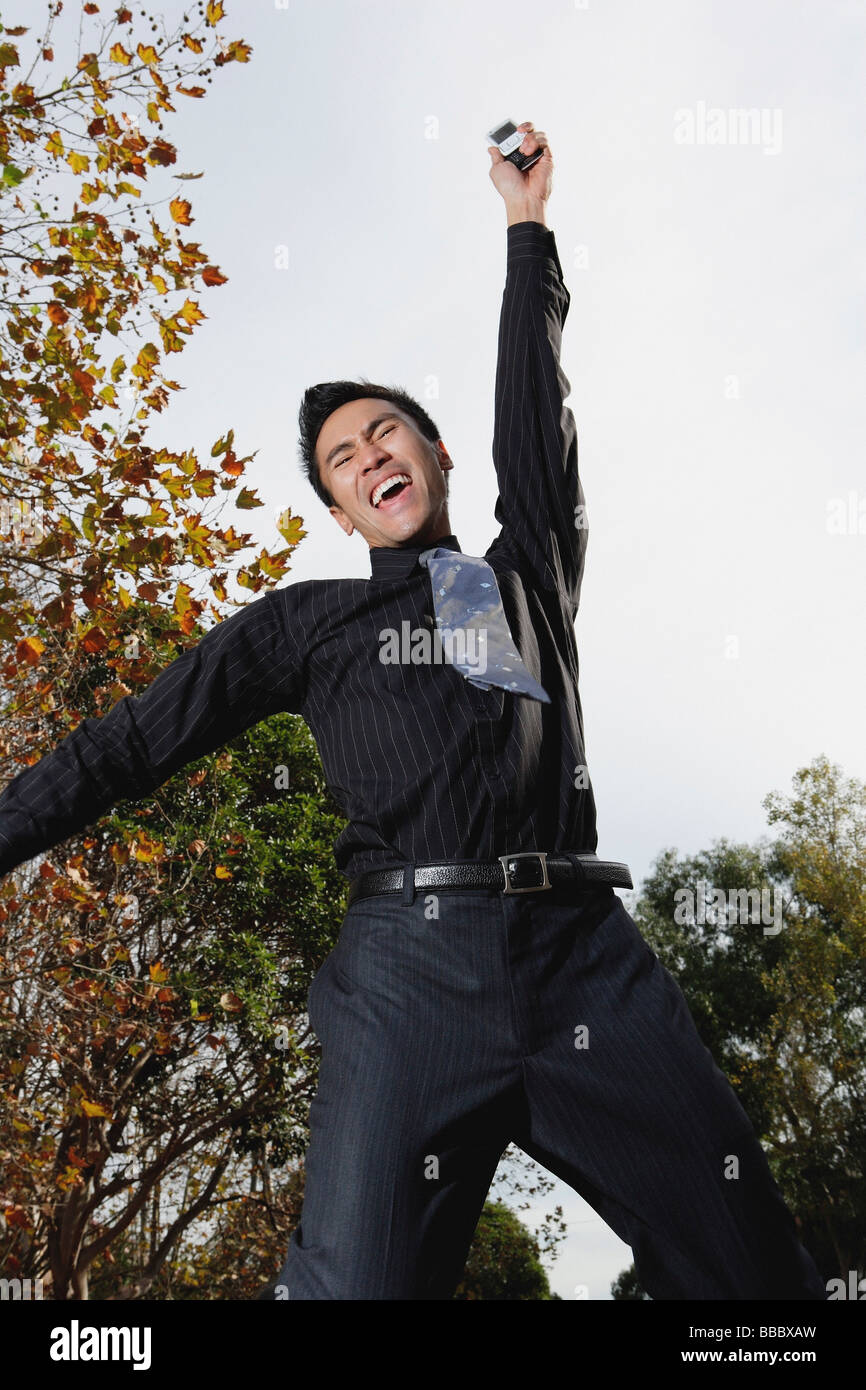 Businessman jumping in air, arm raised in victory Stock Photo - Alamy