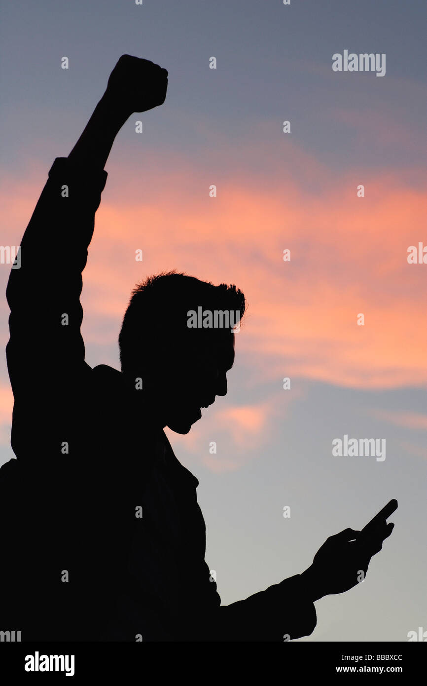 Man standing in silhouette, arm raised in victory Stock Photo - Alamy