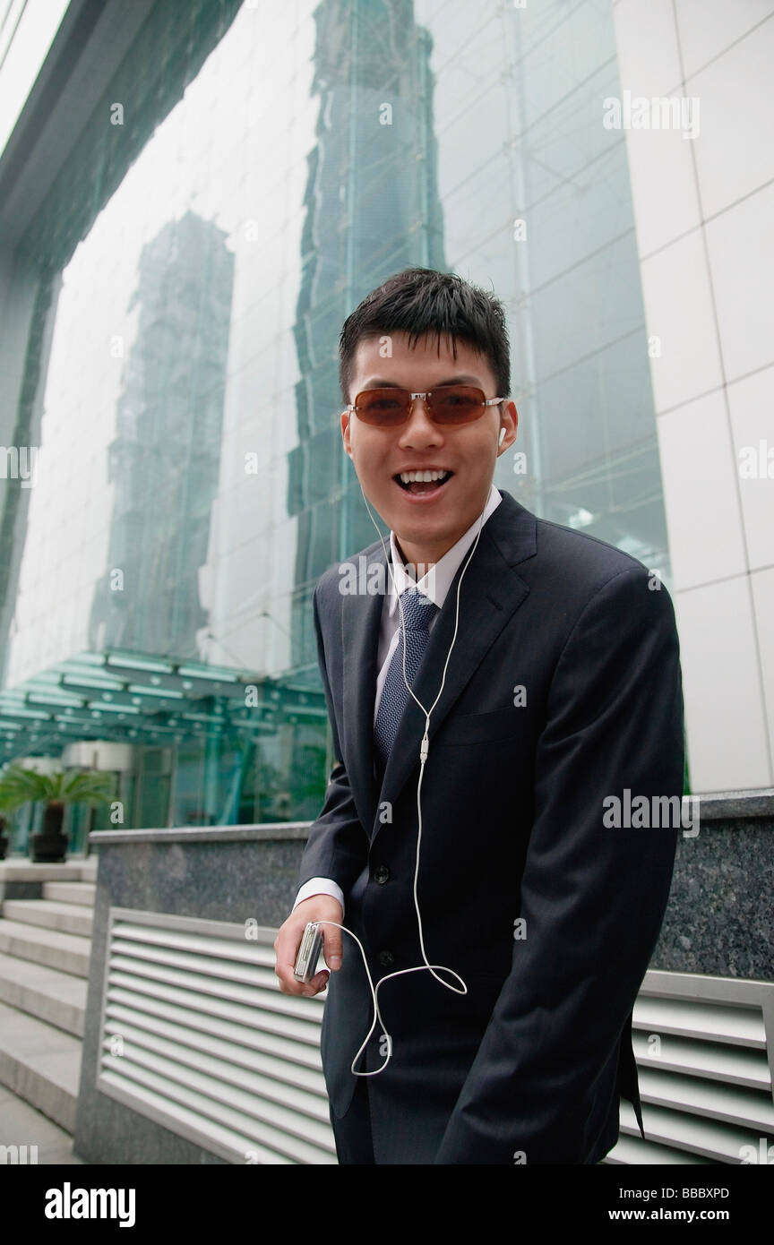 Businessman listening to MP3 player, smiling at camera Stock Photo - Alamy