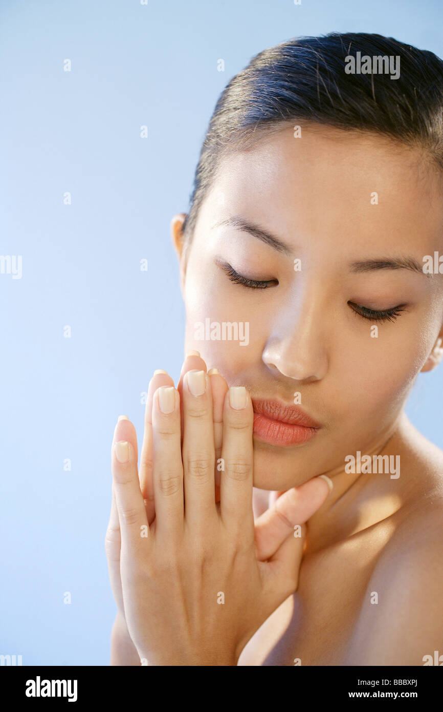 Woman with hands together, eyes downcast Stock Photo - Alamy