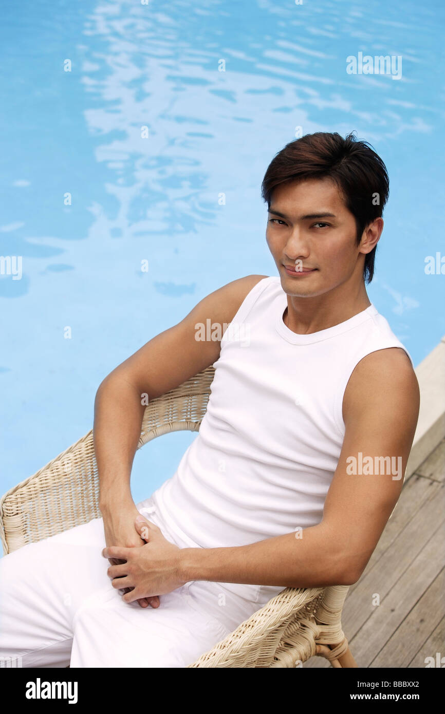 Young man sitting poolside Stock Photo - Alamy
