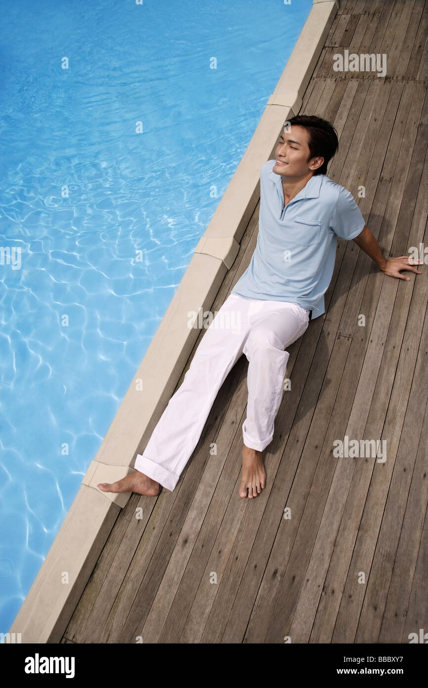 Man reclining by pool Stock Photo - Alamy