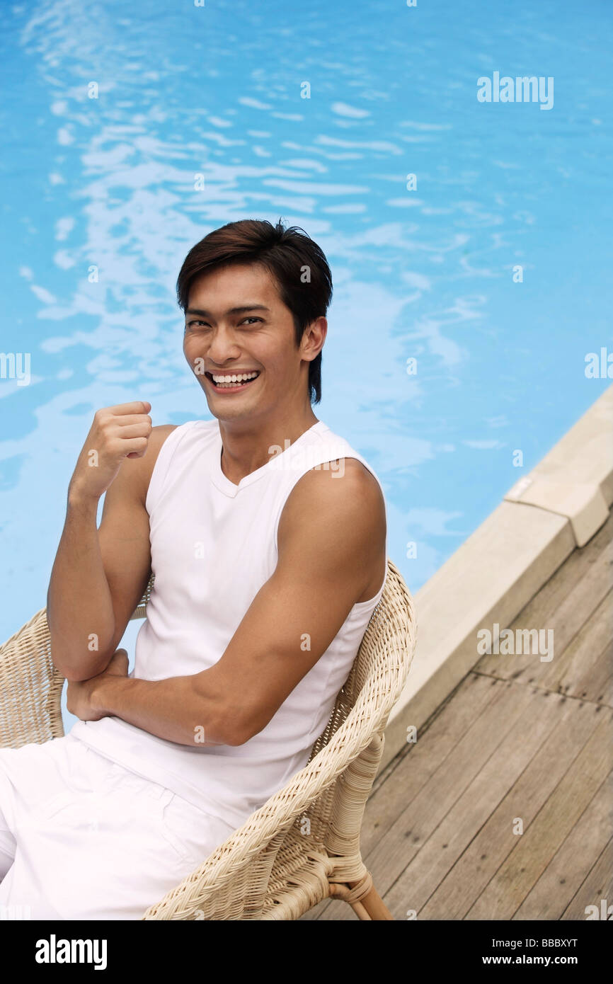 Young man sitting poolside Stock Photo - Alamy