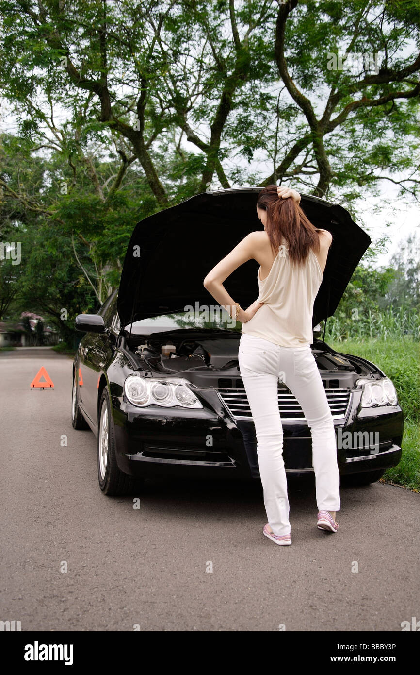 Woman looking under hood of car Stock Photo - Alamy
