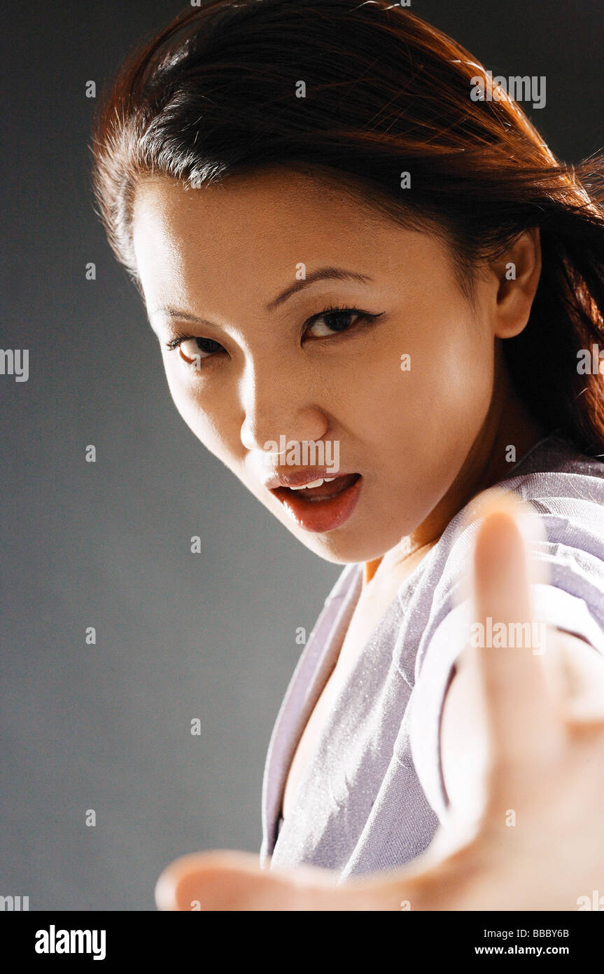 Young woman looking at camera, making a hand sign Stock Photo - Alamy