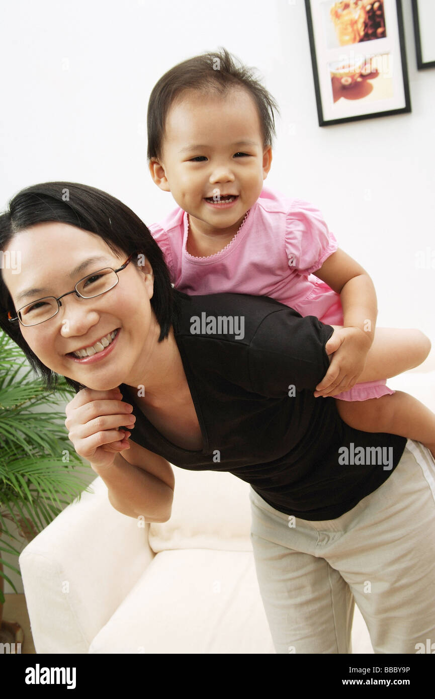 Mother carrying daughter on back Stock Photo - Alamy
