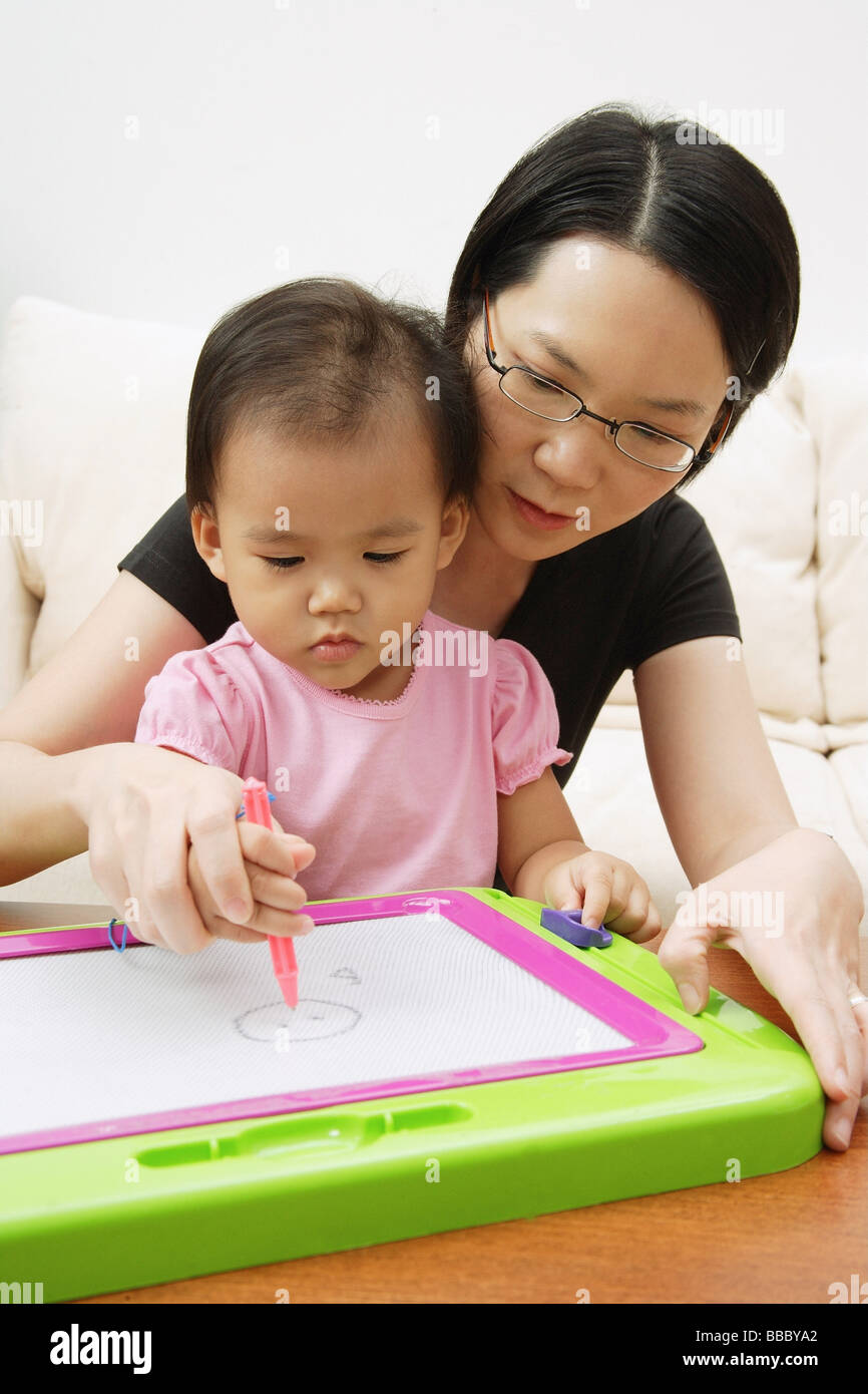 Mother teaching daughter to draw Stock Photo - Alamy