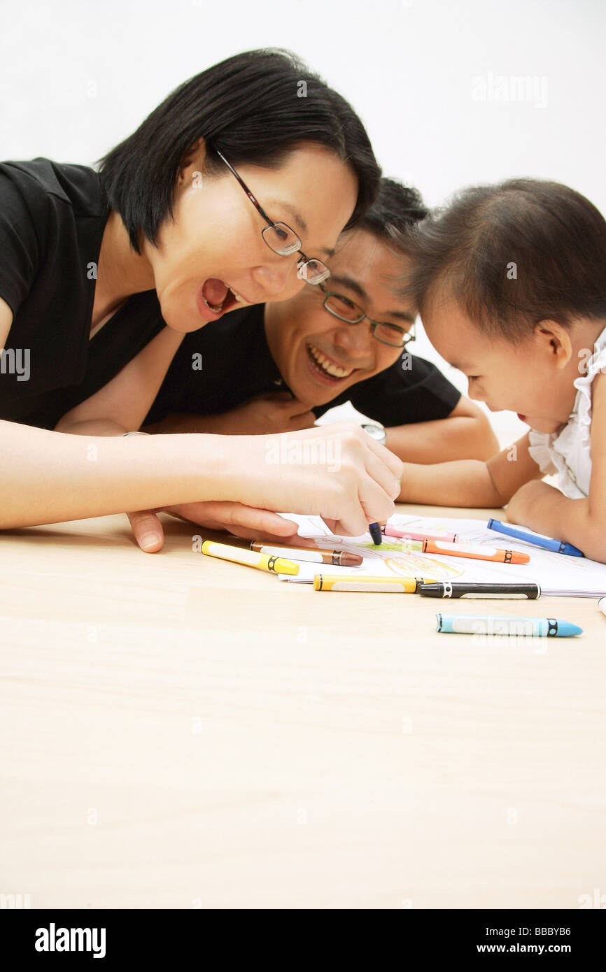 Family with one child drawing with crayons Stock Photo - Alamy
