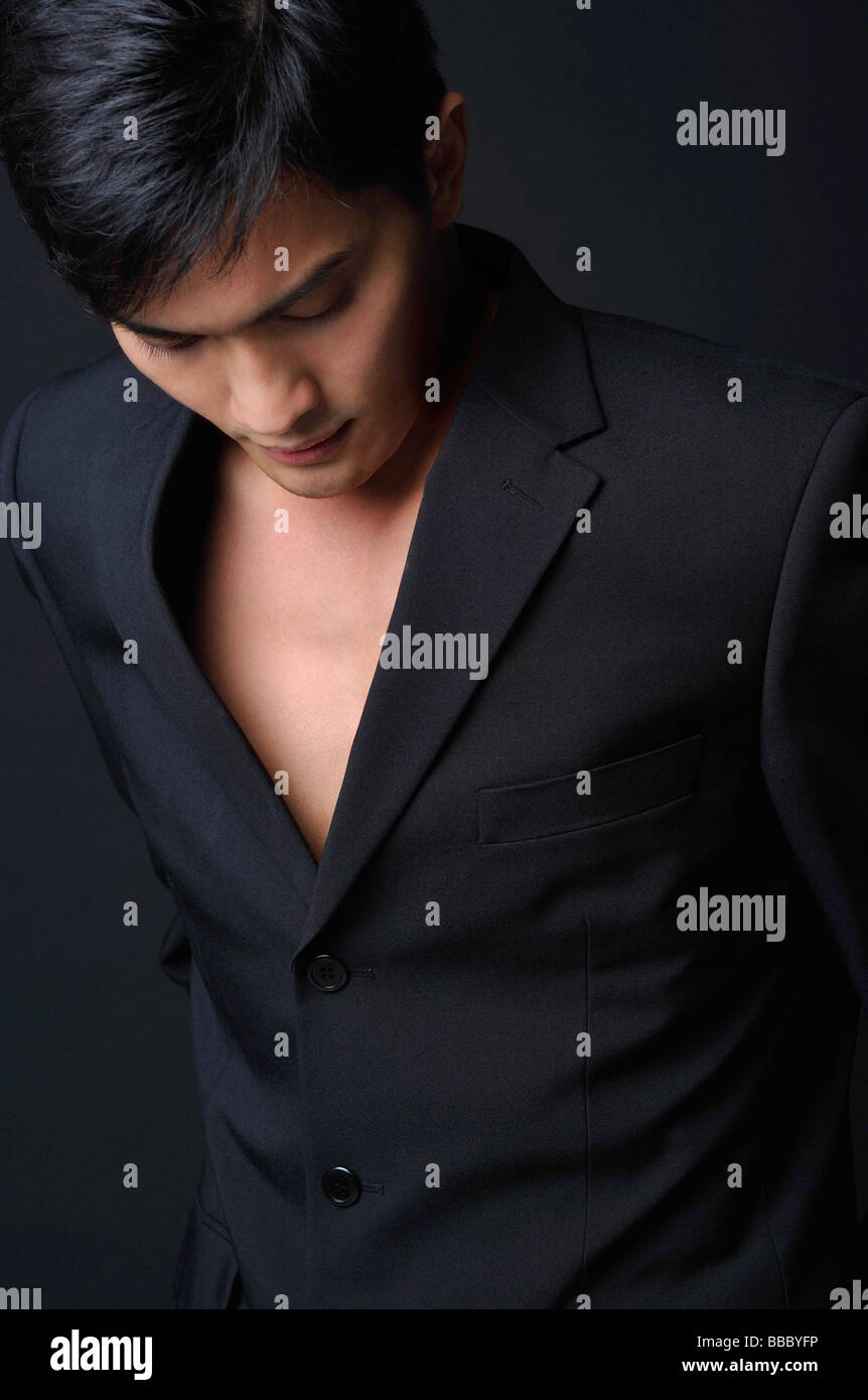 Young man in black suit looking down Stock Photo - Alamy