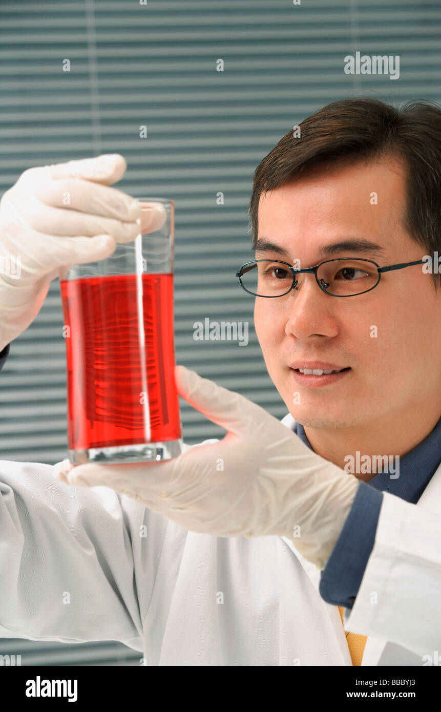 Scientist examining container of fluid Stock Photo - Alamy