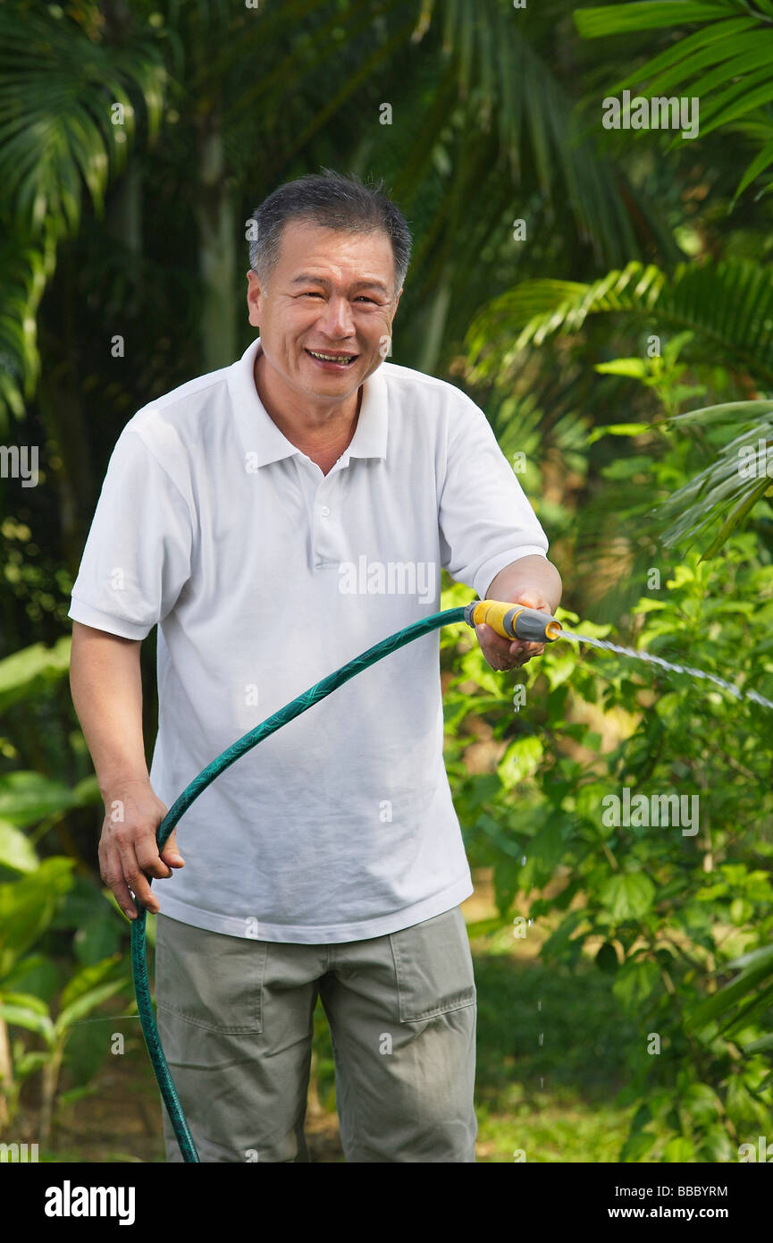 Man with hose, watering garden Stock Photo - Alamy