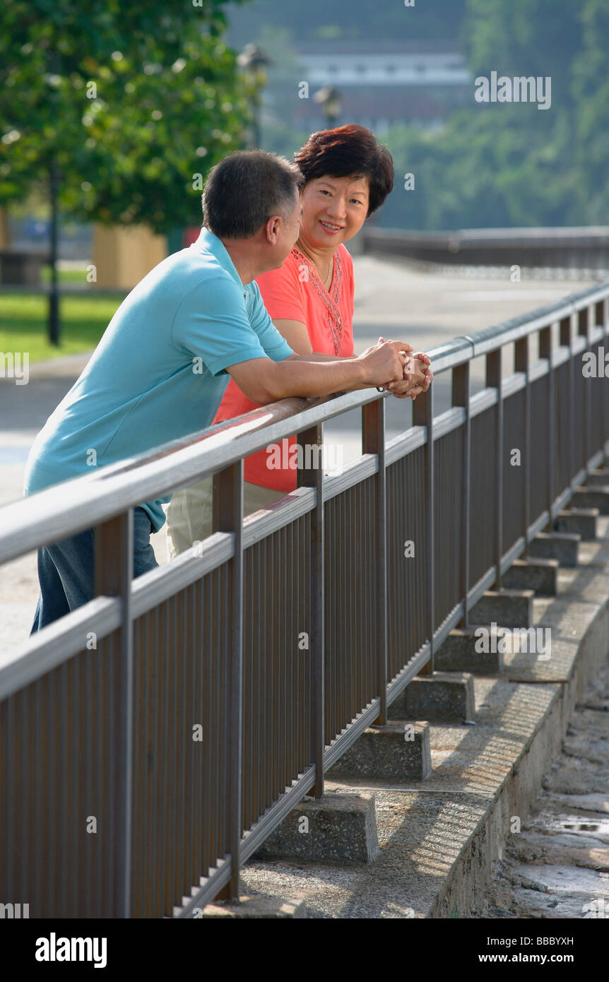 Couple having a conversation while leaning in fence Stock Photo - Alamy