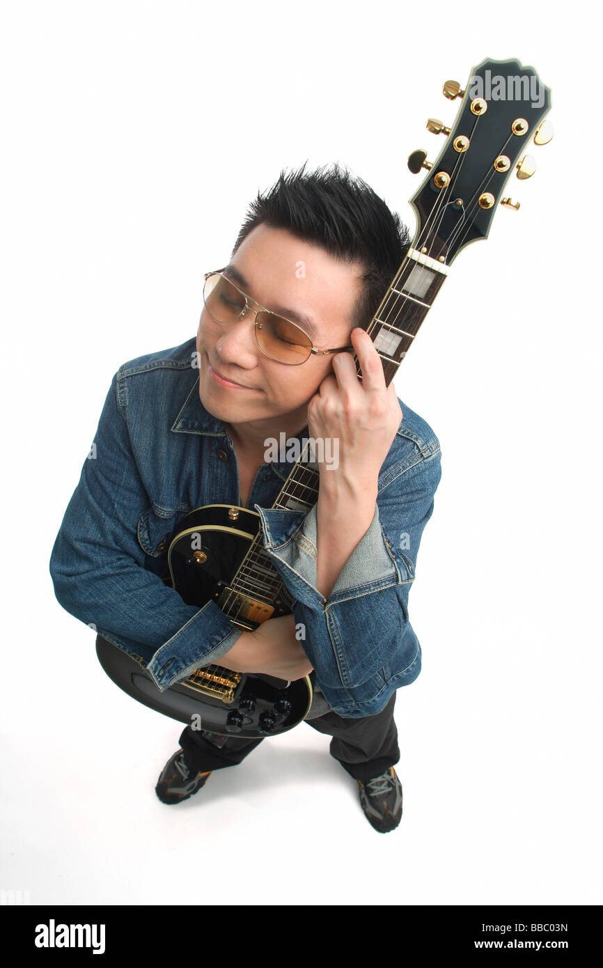 Man smiling while hugging his guitar Stock Photo - Alamy