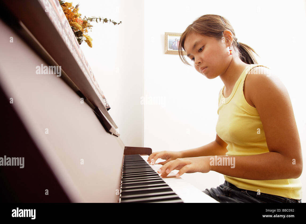 Young woman sitting at piano, looking down Stock Photo - Alamy