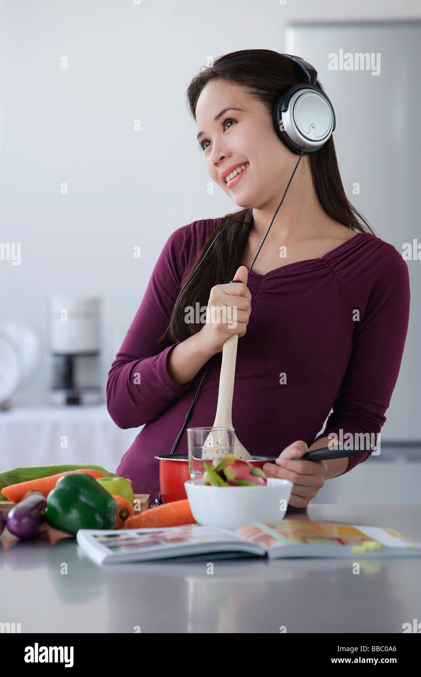 Young woman cooking while listening to music Stock Photo - Alamy