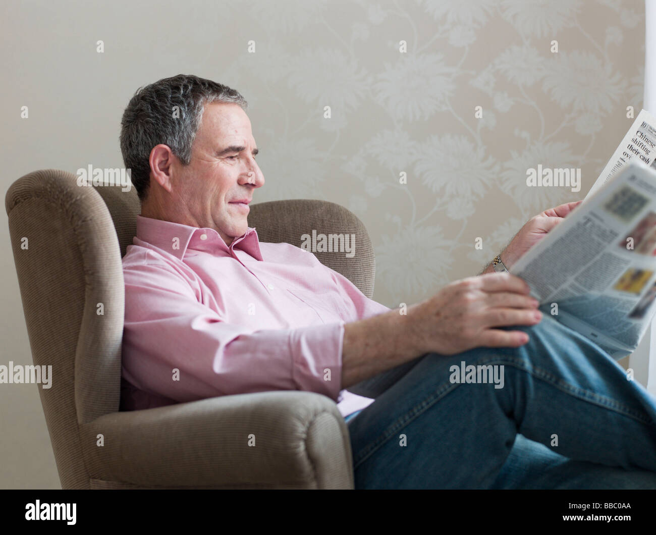 man reading paper sitting in chair Stock Photo - Alamy
