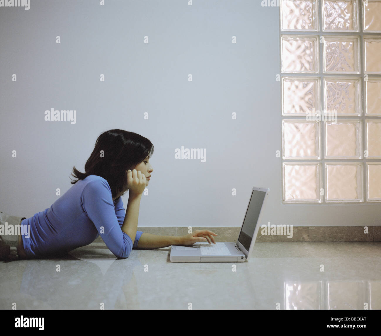 Young woman lying on floor looking at laptop monitor Stock Photo - Alamy