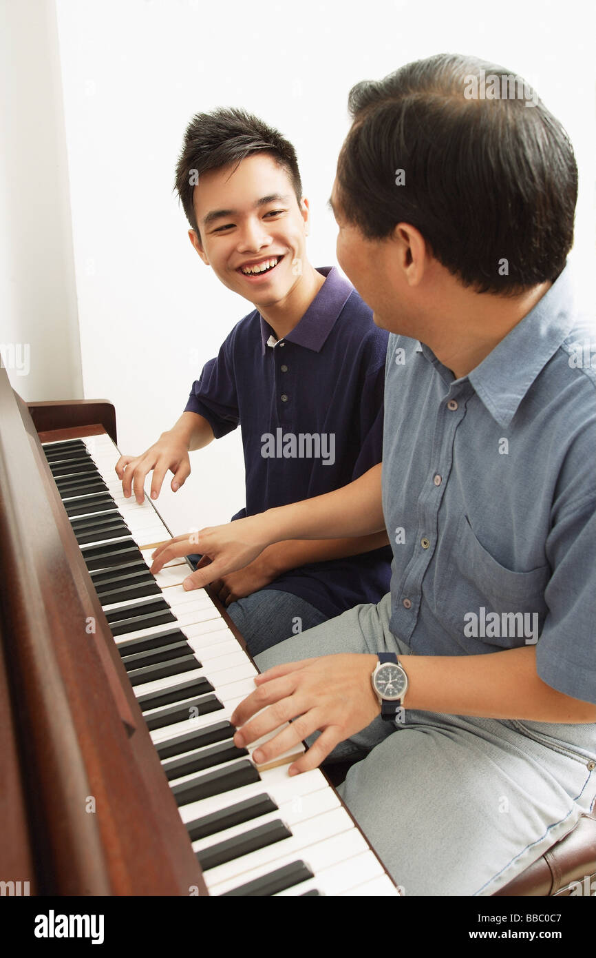 Father and son playing piano, side by side Stock Photo - Alamy