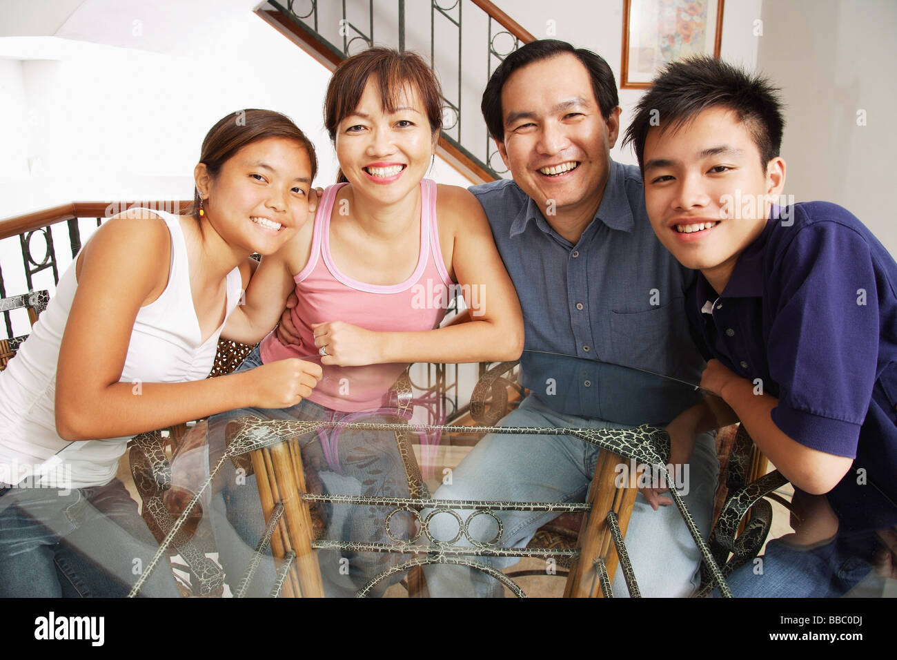 Family at home, sitting side by side, looking at camera Stock Photo - Alamy