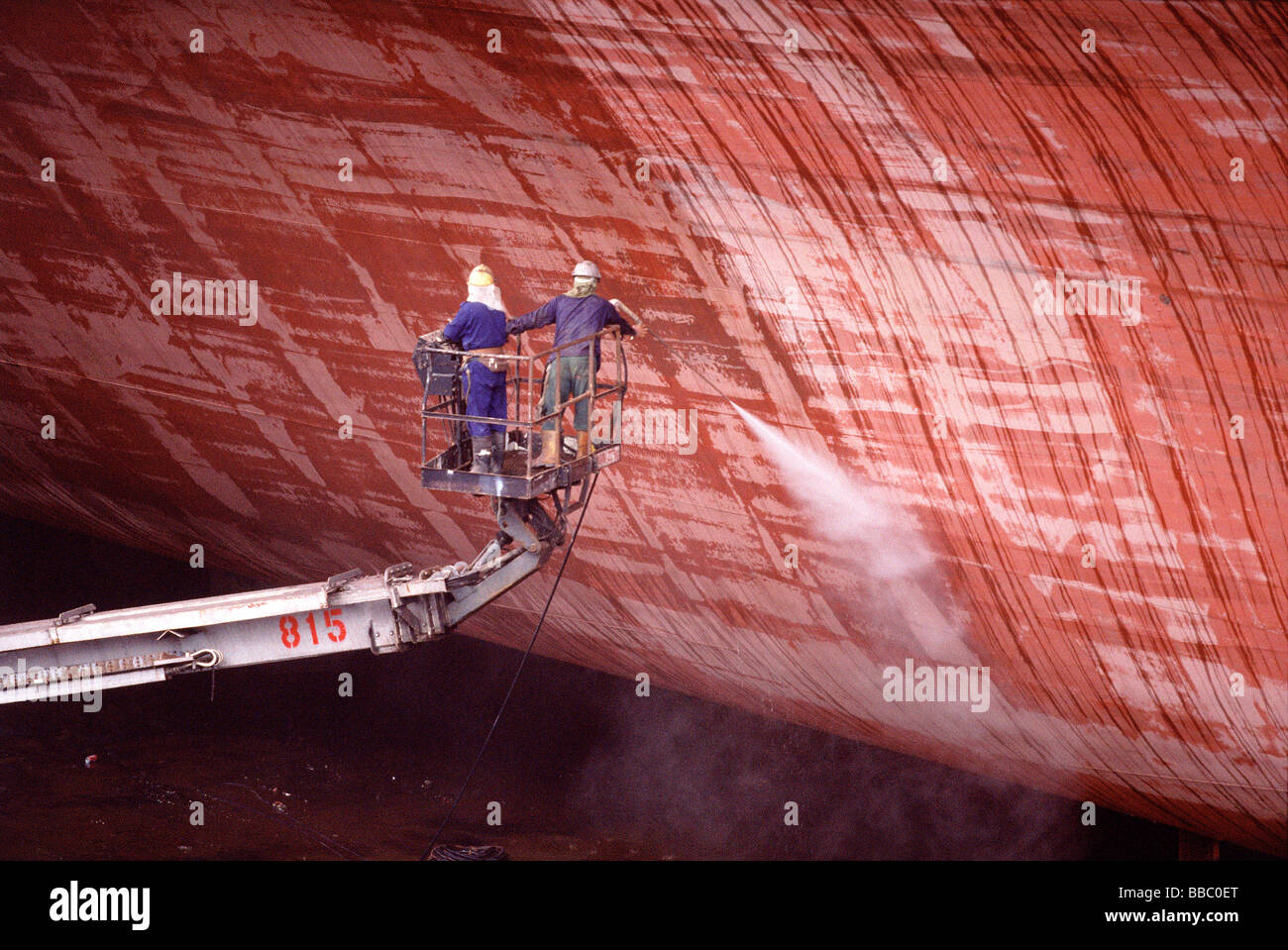 Workers cleaning side of ship at shipyard Stock Photo - Alamy