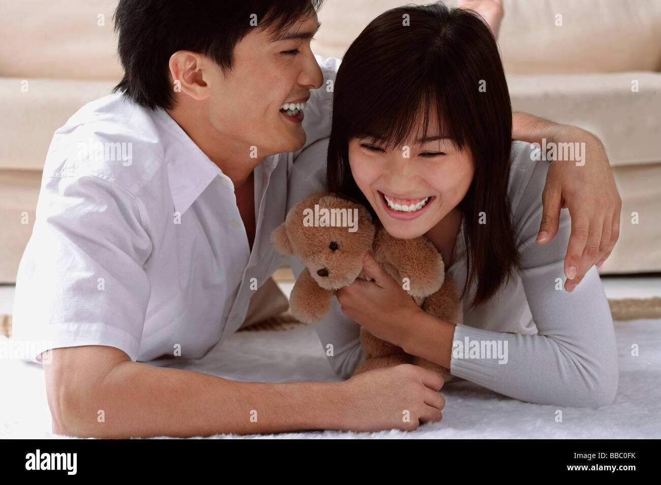 Young couple laughing while hugging and lying on the floor Stock Photo ...