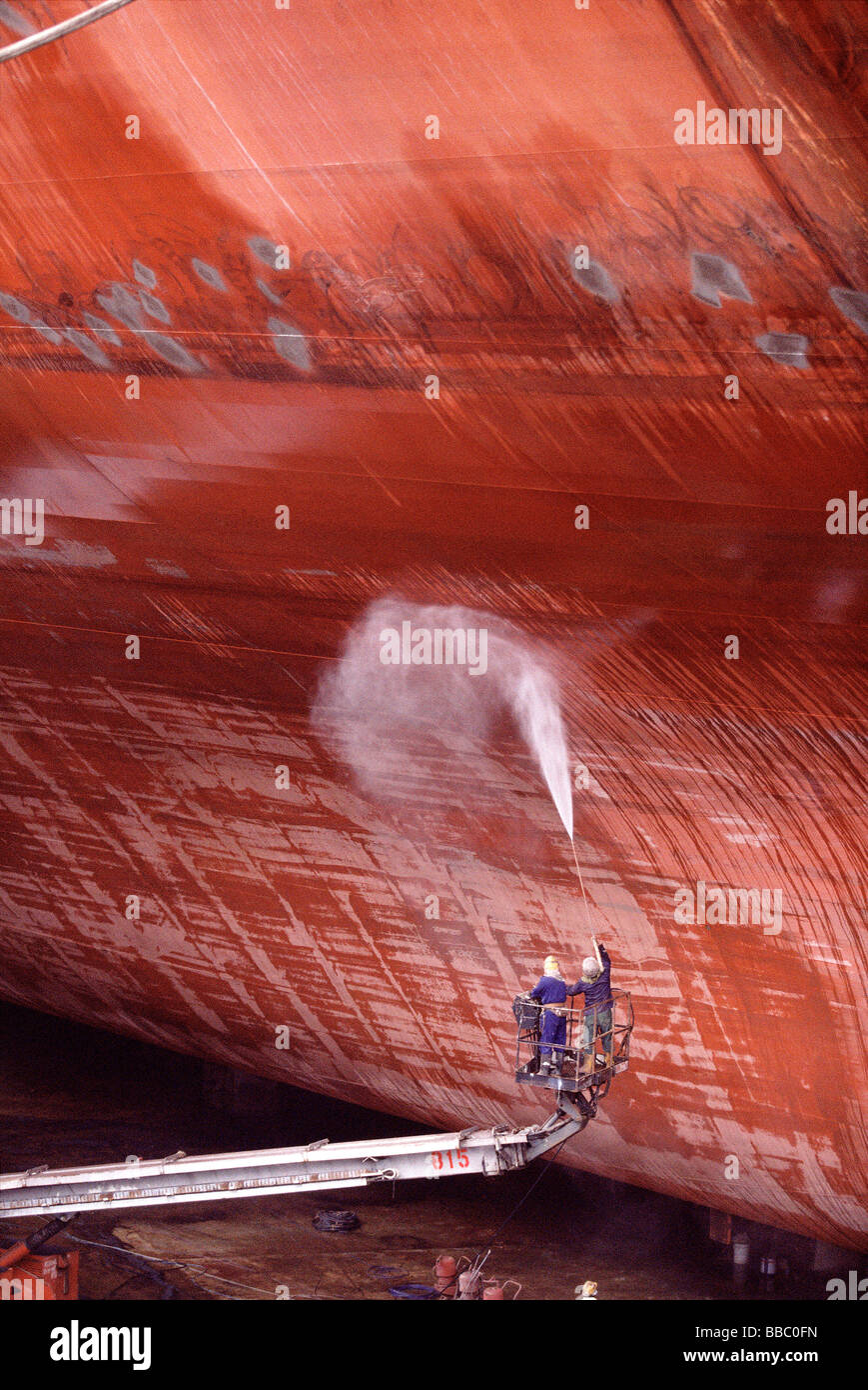 Workers cleaning side of ship at shipyard Stock Photo - Alamy