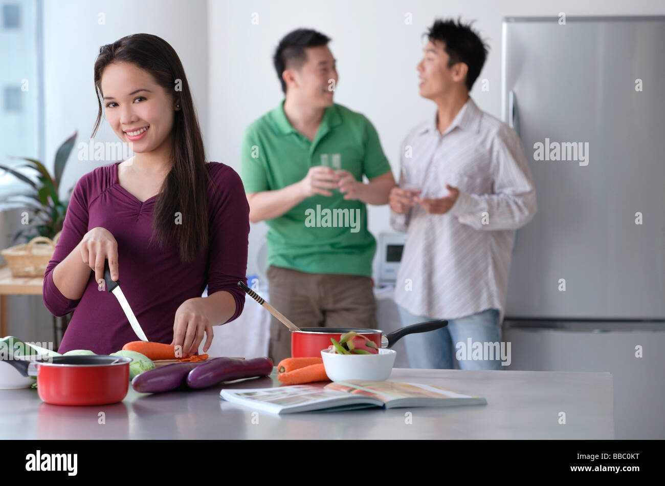 Woman cooking while men talk Stock Photo - Alamy