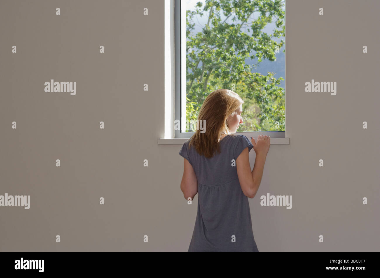 Woman looking out of window Stock Photo - Alamy