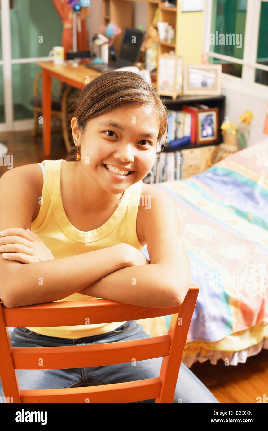 Young woman with arms folded, sitting on chair, looking at camera Stock ...