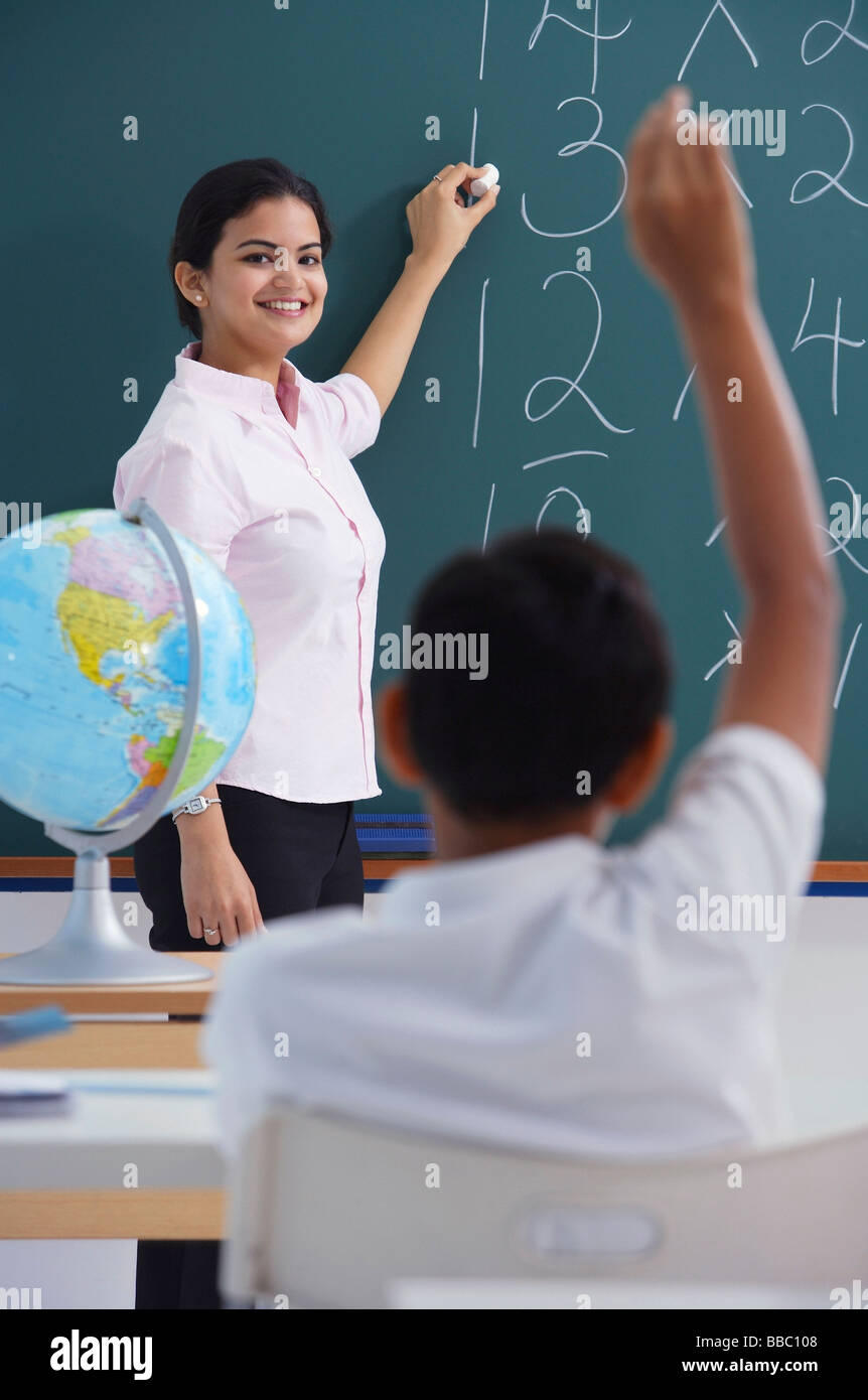 teacher at chalkboard, boy raises hand Stock Photo - Alamy