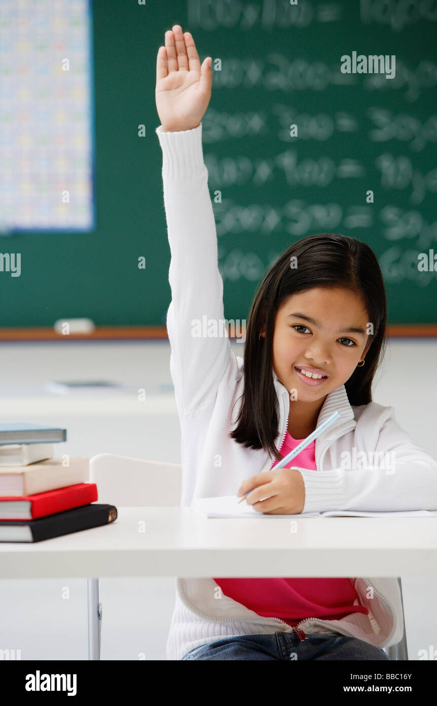 Girl raising hand in class Stock Photo - Alamy
