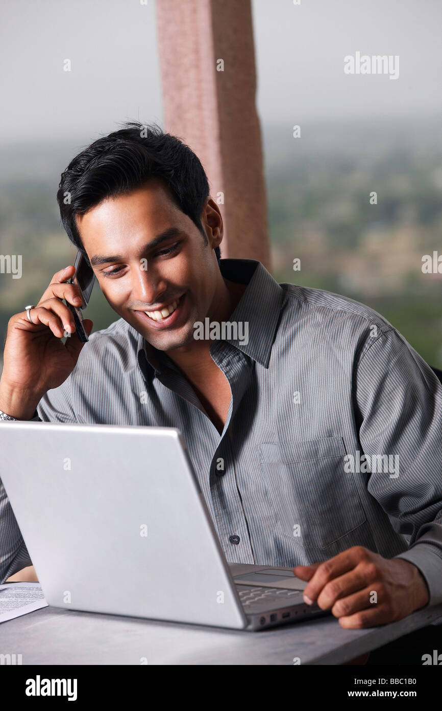 man on phone, working at laptop computer Stock Photo - Alamy