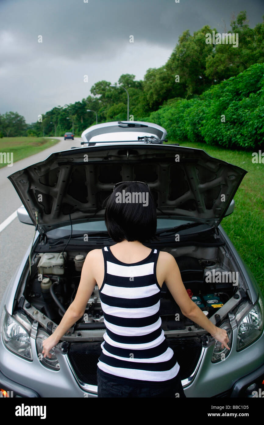 A woman checks under the hood of her car Stock Photo - Alamy