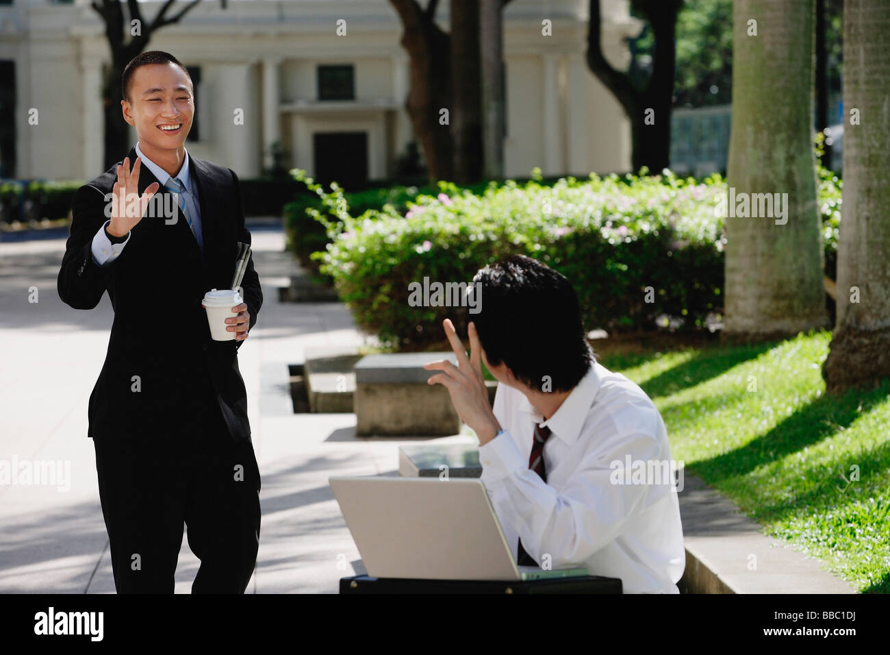 Two men wave at each other in the park Stock Photo - Alamy