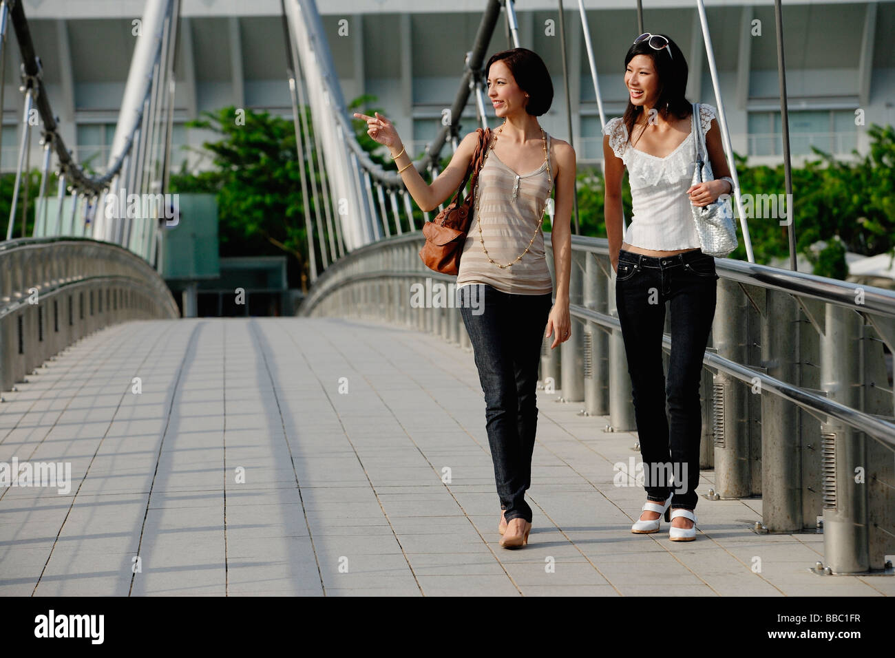 Two friends walk across a bridge together Stock Photo - Alamy