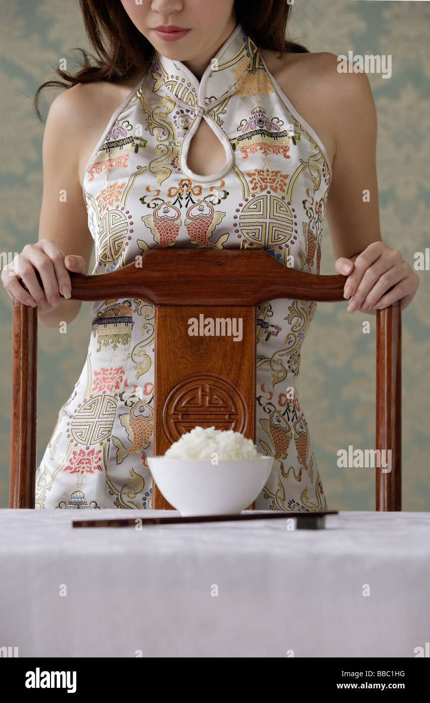 Young woman behind chair with bowl of rice on table Stock Photo - Alamy