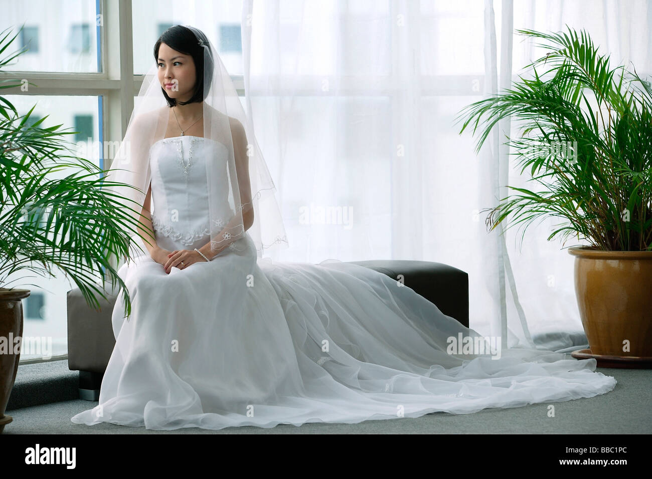 A bride with a white wedding gown sits down Stock Photo - Alamy