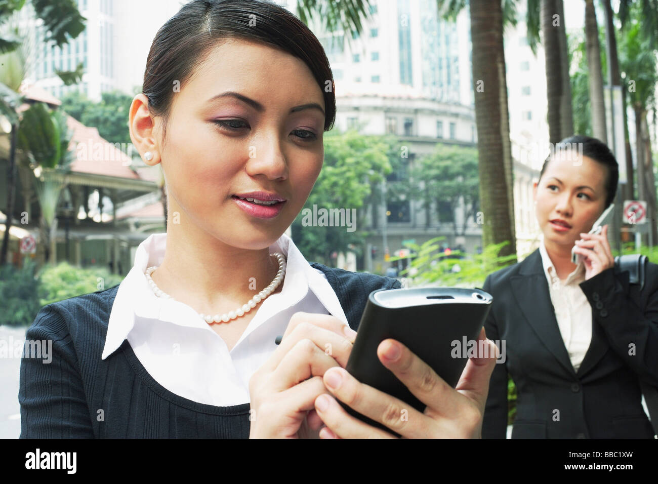 Business woman using PDA, woman in the background on the phone Stock ...