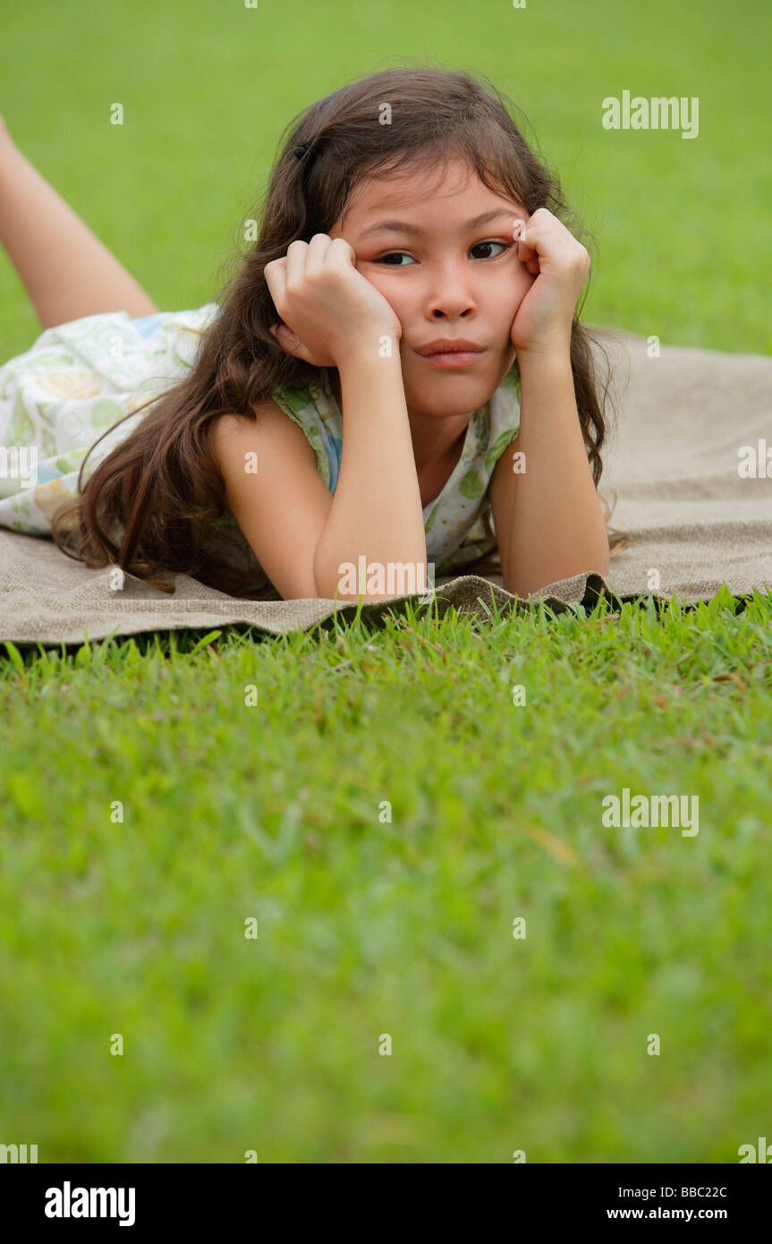 Girl lying on picnic blanket, hands on face, sad expression Stock Photo ...